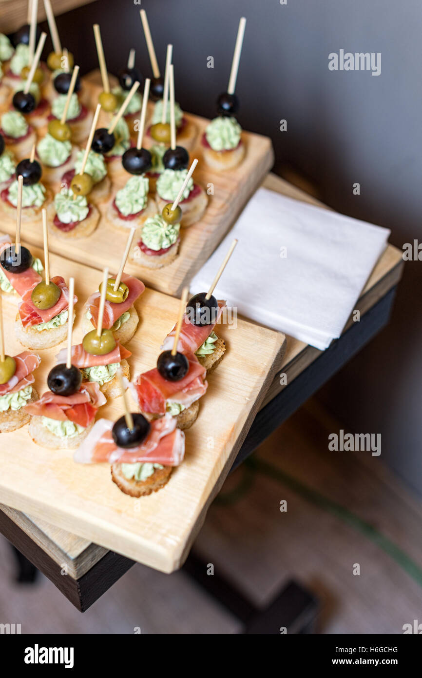 Wooden tray of appetizers on pallet coffee table at banquet with jamon ...