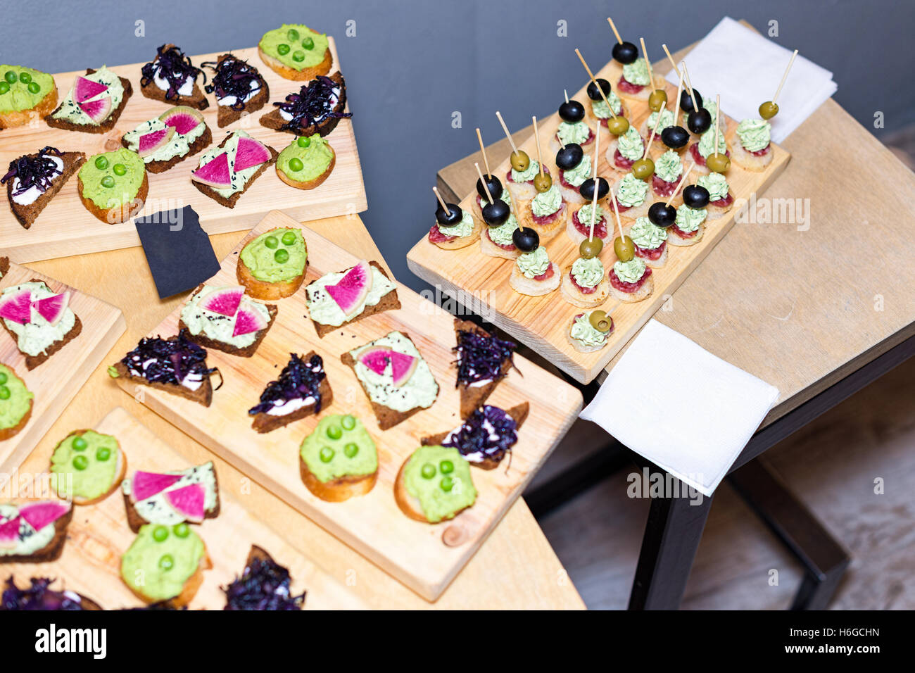 Wooden tray of appetizers on pallet coffee table at banquet with jamon ...