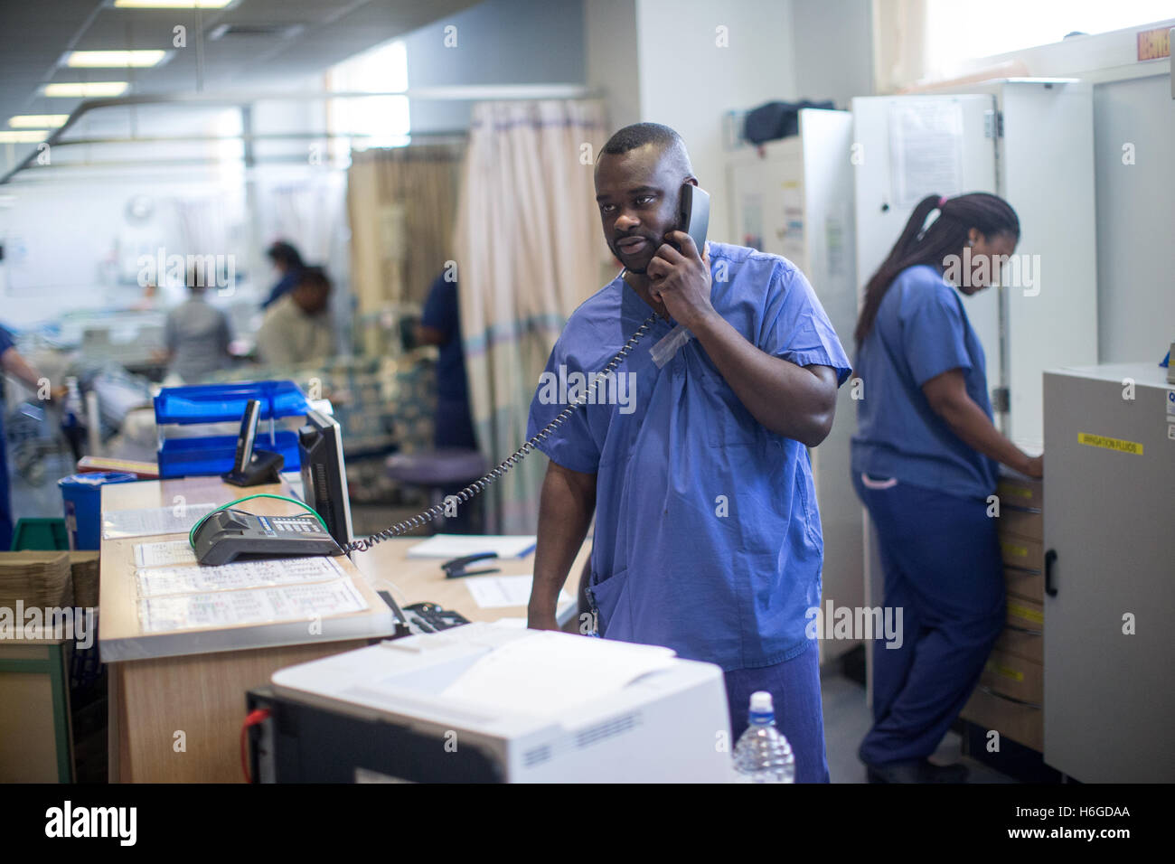 Hospital nurse at a workstation in a ward answering enquiries and ...