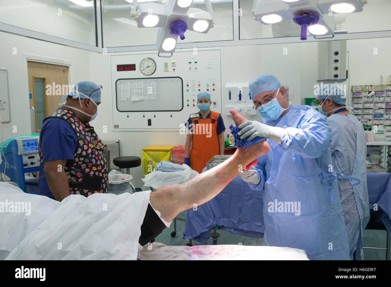 A surgeon and staff prepare a patient for surgery prior to performing ...