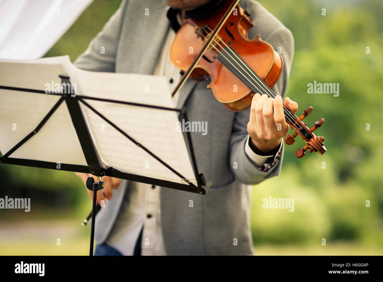 Male violinist playing his instrument and reading a music sheet during ...