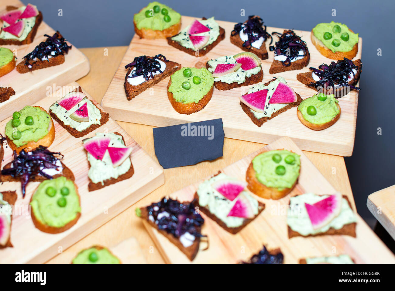 Wooden tray of appetizers on pallet coffee table at banquet with paper ...