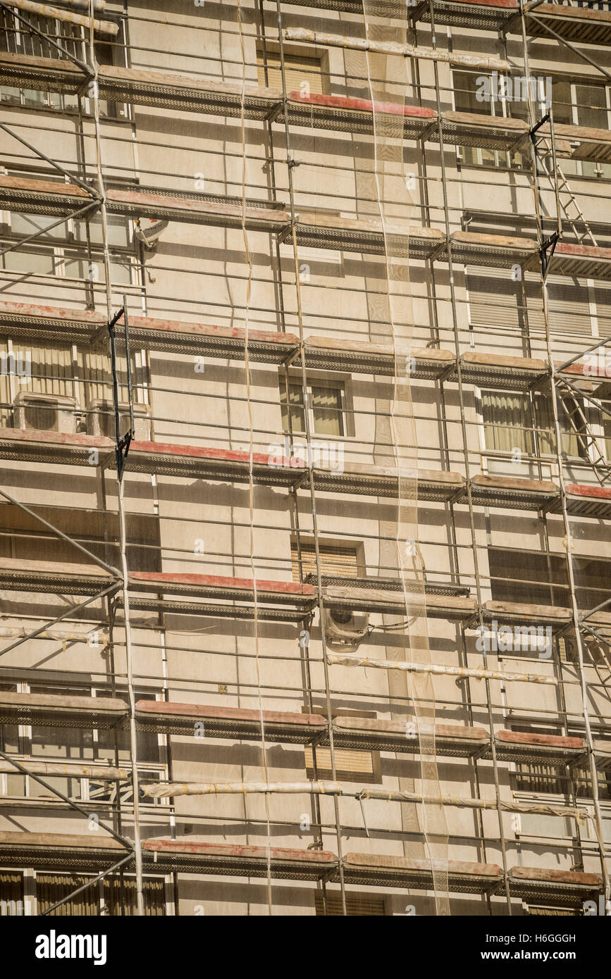 Scaffolding and netting covering the facade of a tall building being ...