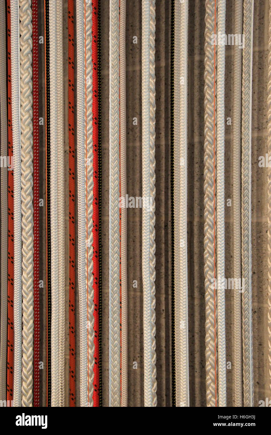 Vertical image of bright and colorful braided ropes hanging on wall of ...