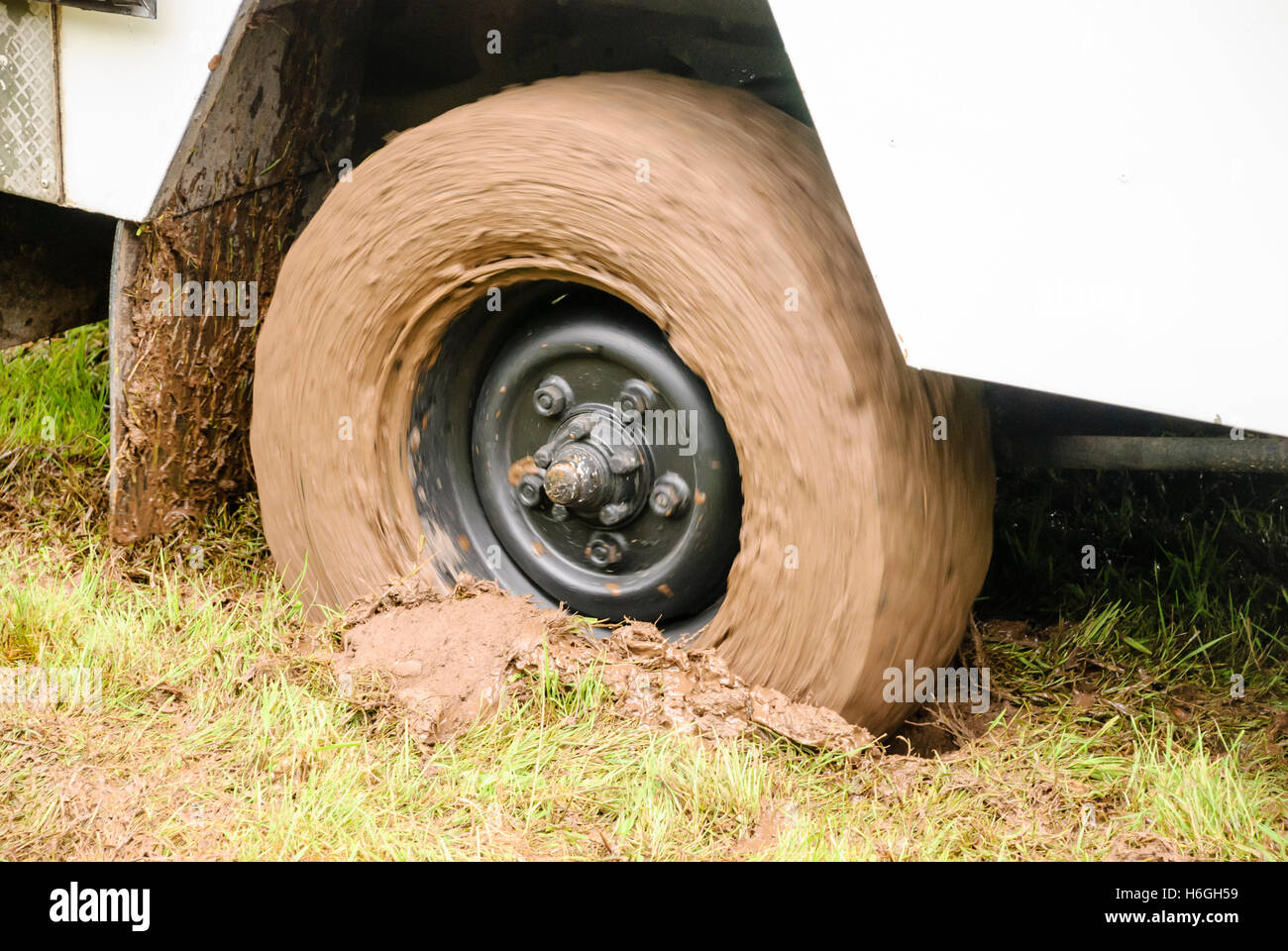 Wheel of a truck lorry spinning as it is stuck in deep mud soft grass ...