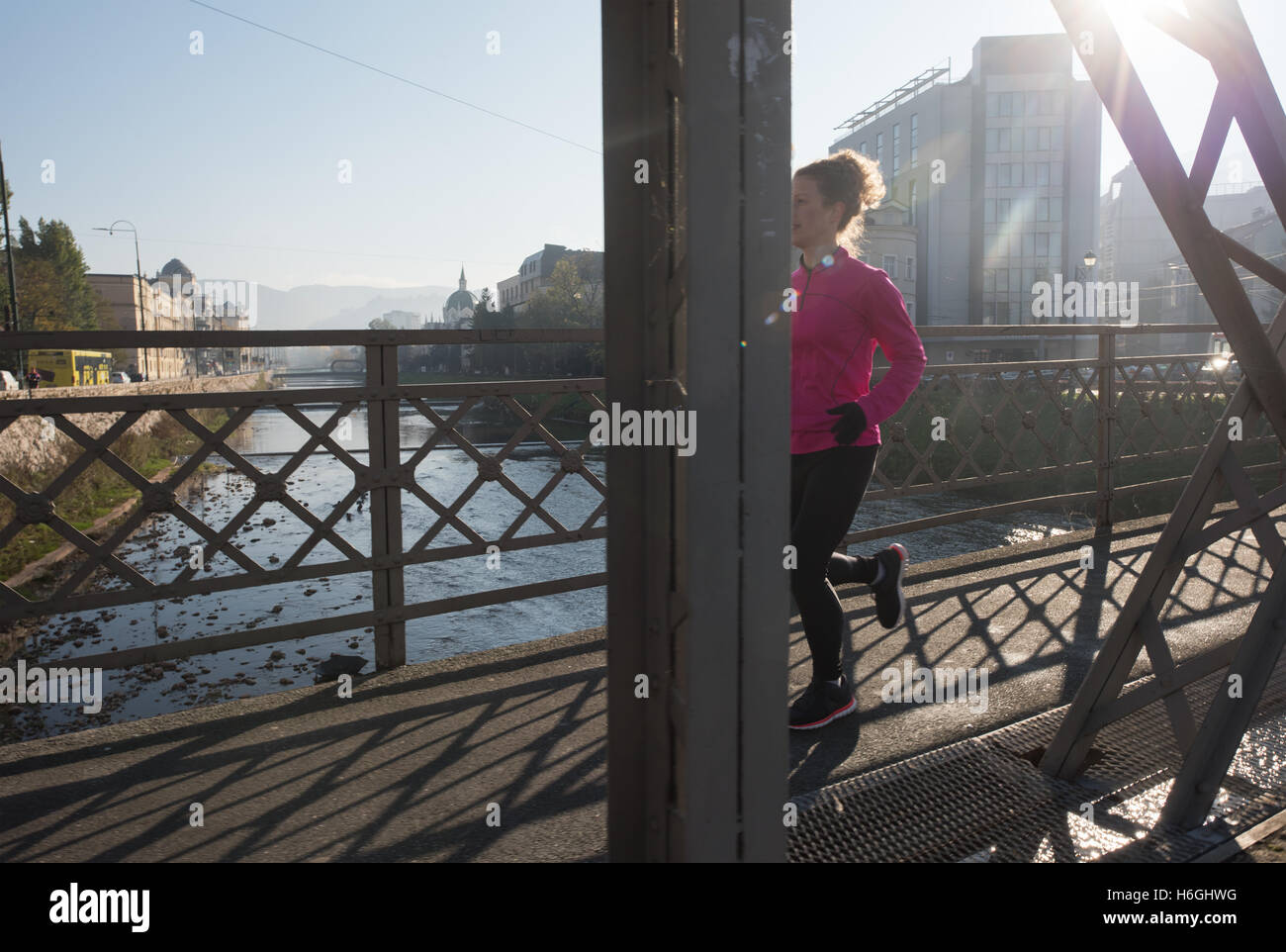 sporty woman running on sidewalk at early morning jogging with city ...