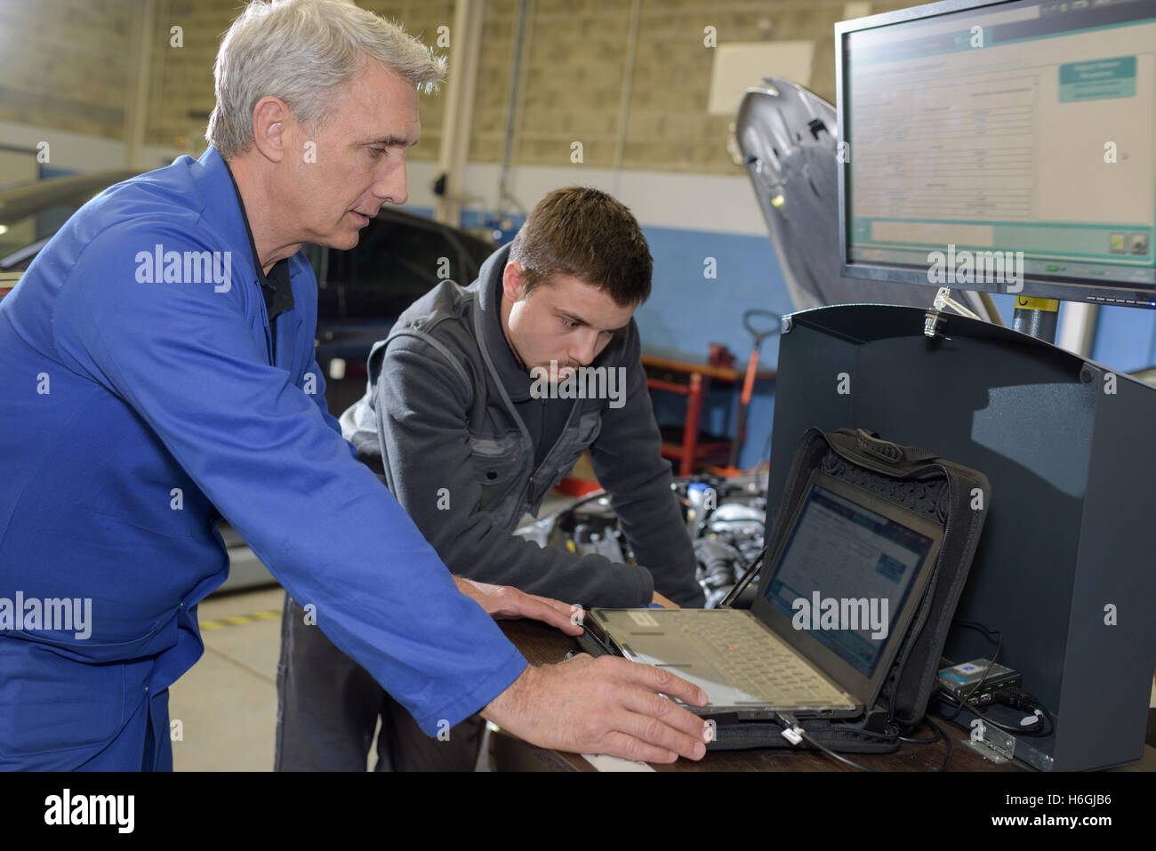 auto mechanic teacher and trainee performing tests at mechanic school ...