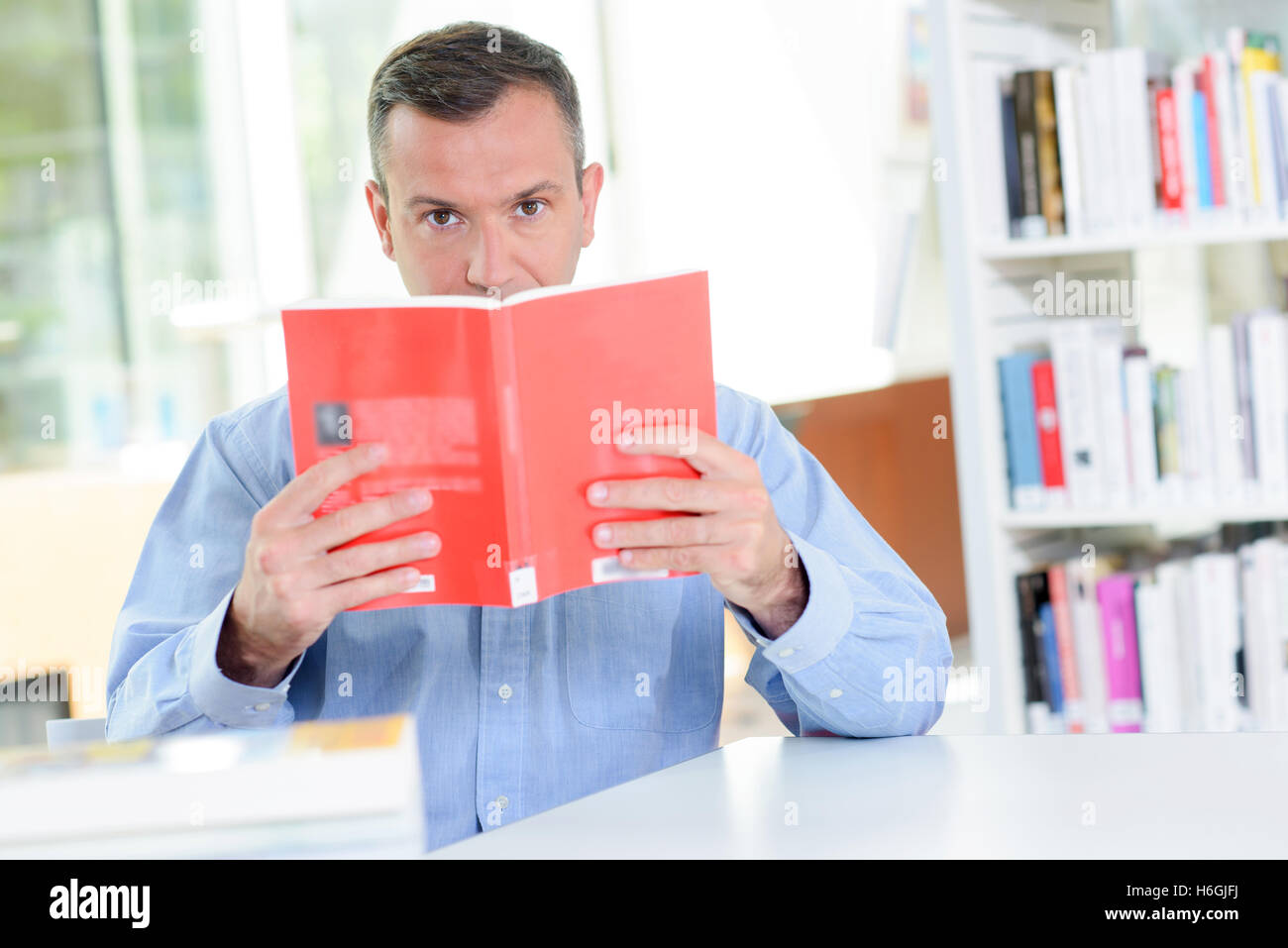 Man looking over top of book Stock Photo - Alamy