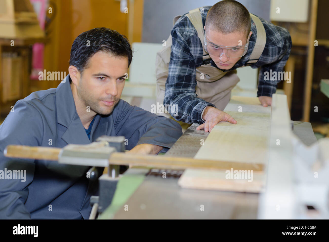 Men lining up plank of wood Stock Photo - Alamy
