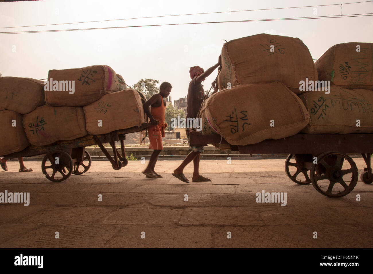 coolies push and pull great carts loaded with packs of goods on ...