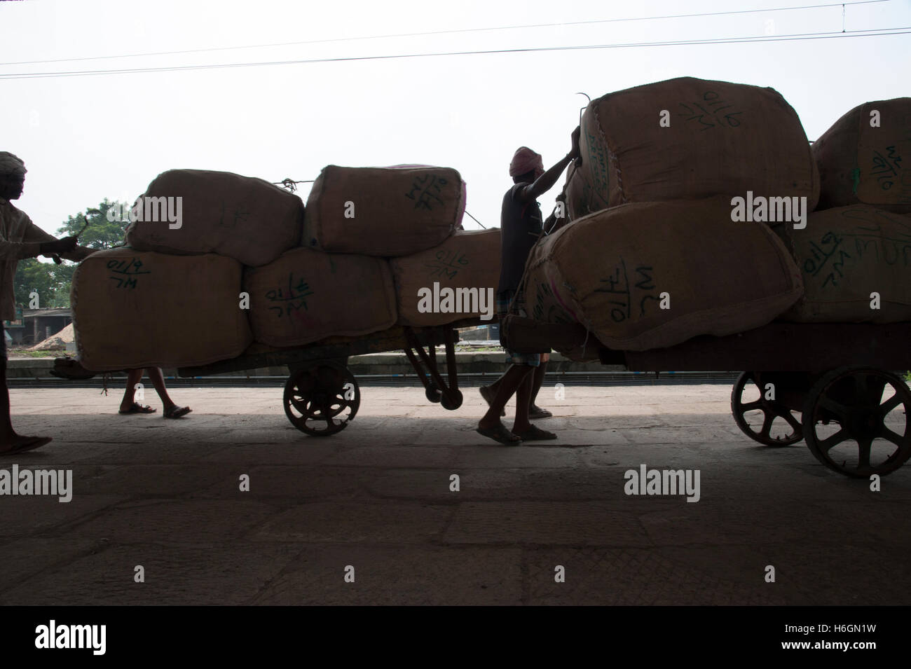coolies push and pull great carts loaded with packs of goods on ...