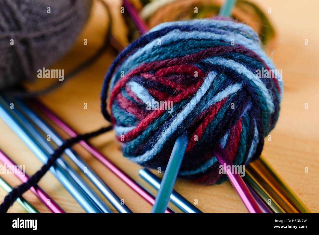 Horizontal photo with ball of multi color wool with knitting needles ...