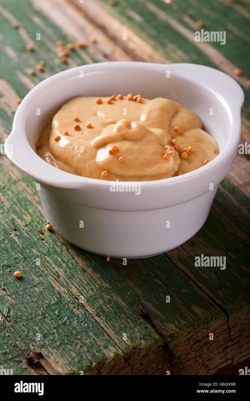 Vertical photo of bowl with mustard. White oval bowel full of orange ...