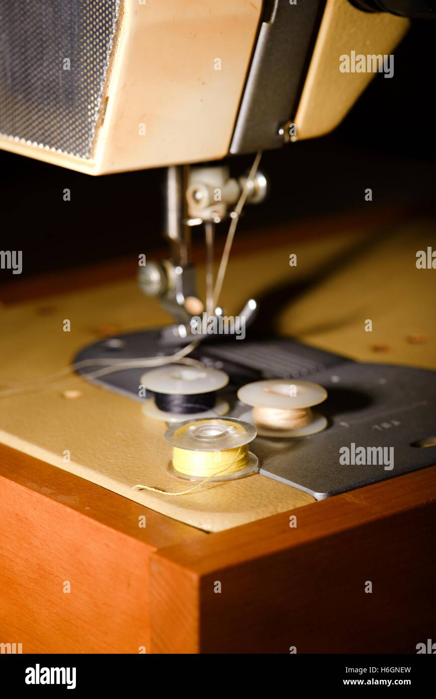 Vertical photo of old sewing machine where are placed three small coils ...
