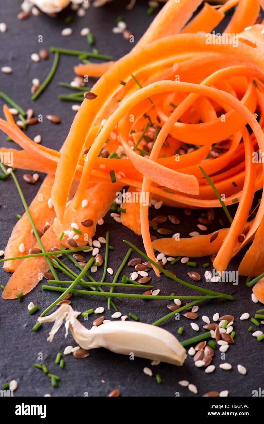 Vertical photo with heap of several carrot shavings. Spilled sesame and ...