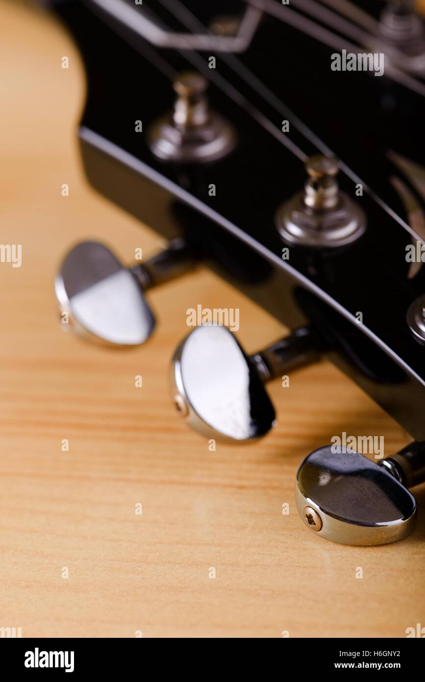 Vertical photo of guitar tuners on black head. Instrument is placed on ...