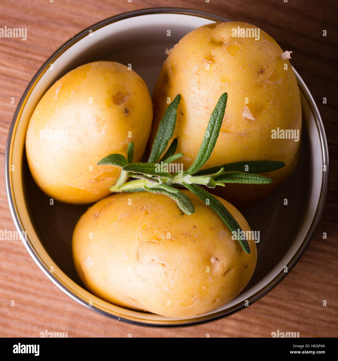 Square photo of old rustic pot with three potatoes which are raw ...
