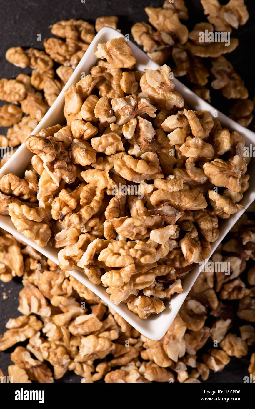 Vertical photo with top view on walnuts in white modern bowl. Few nuts ...