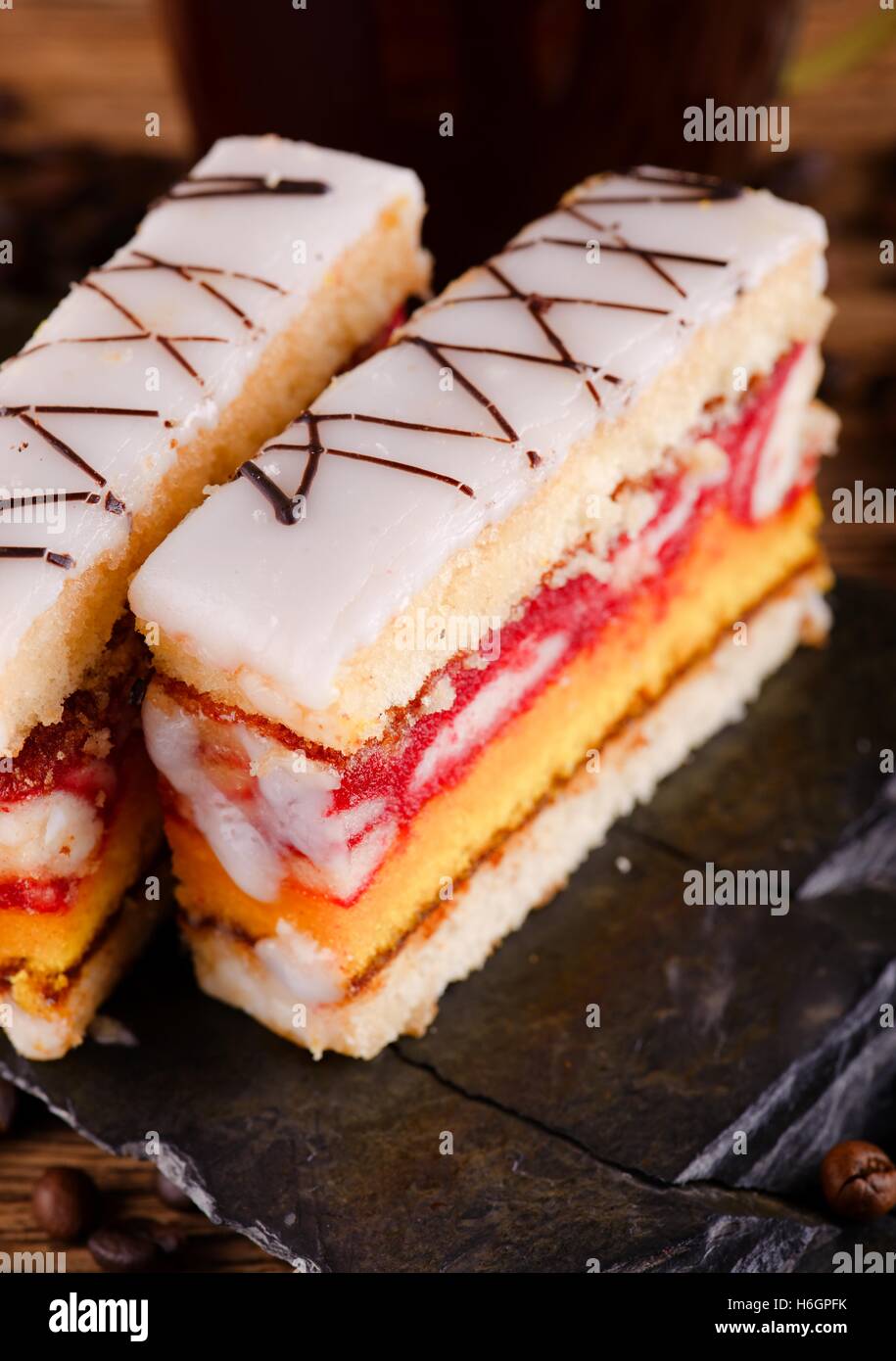 Vertical photo of two slices of sweet desert with color layers on sugar ...