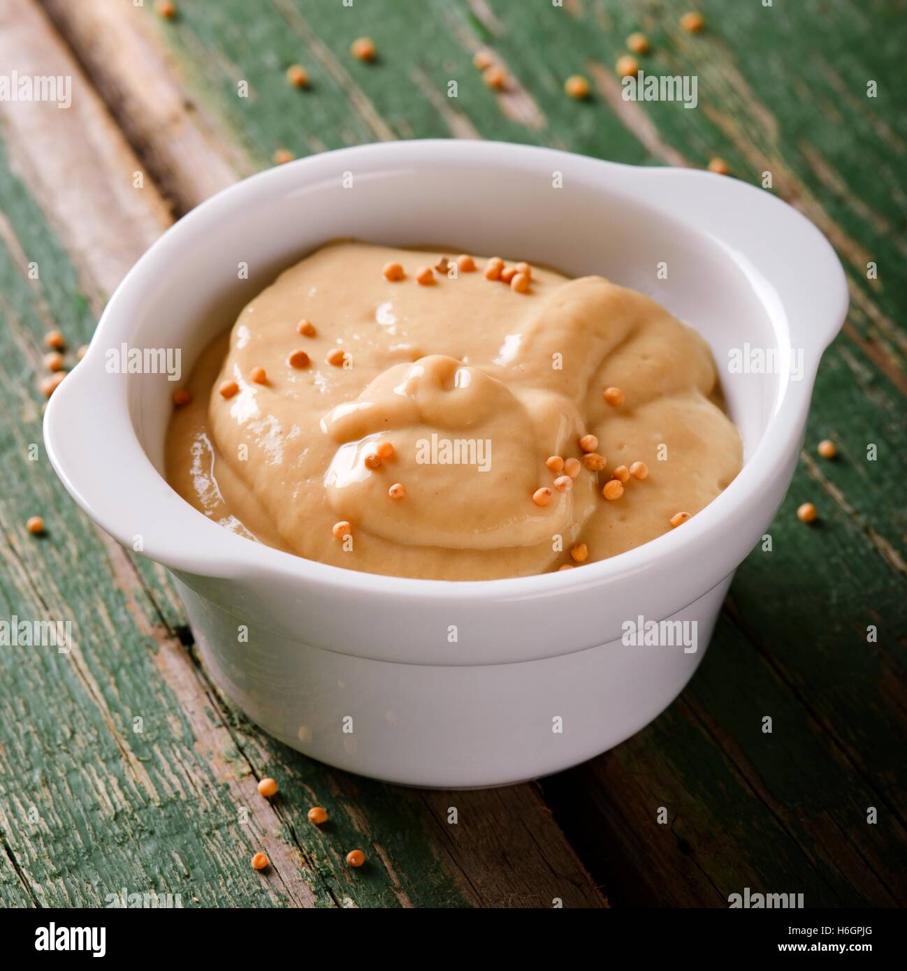 Square photo of bowl with mustard. White oval bowel full of orange ...
