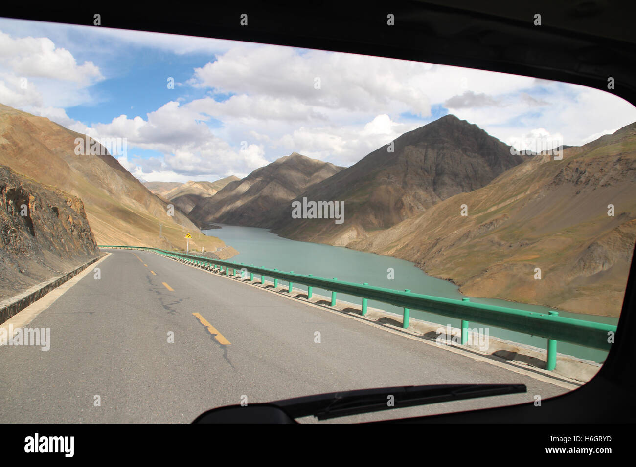 Road running through mountains and lake from a car's back window in ...