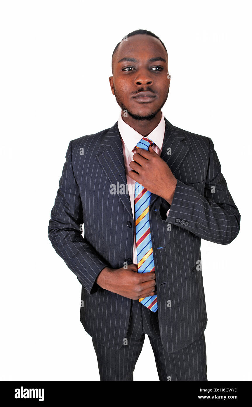 A young black business man standing in a suit and tie, fixing his tie ...