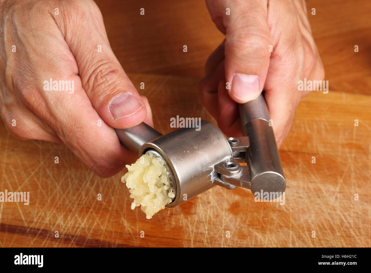 Garlic crushing using a garlic press Stock Photo - Alamy
