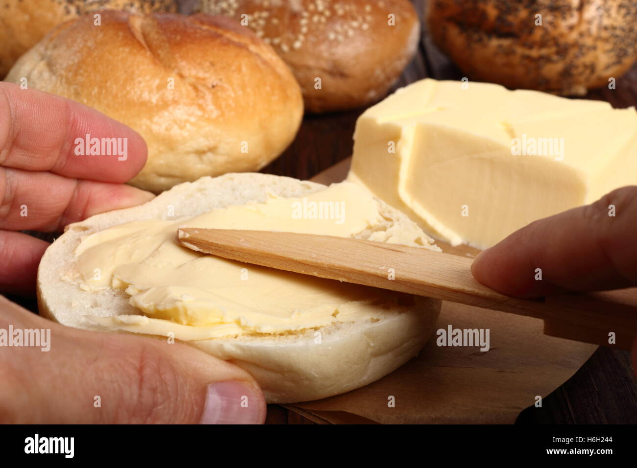 Spreading butter on bread roll Stock Photo - Alamy