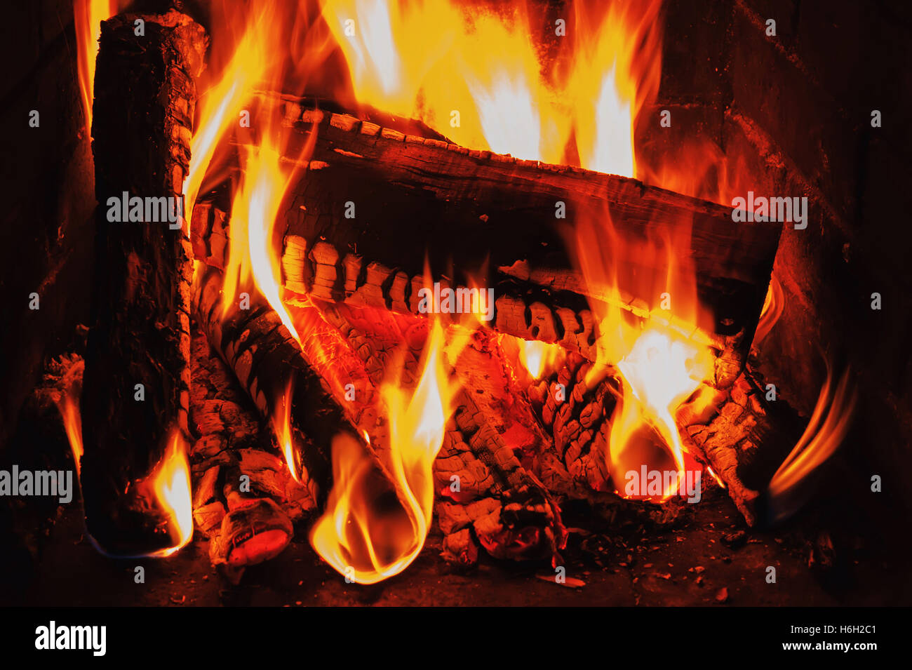 Fireplace with wood brick and fire. Closeup Stock Photo - Alamy