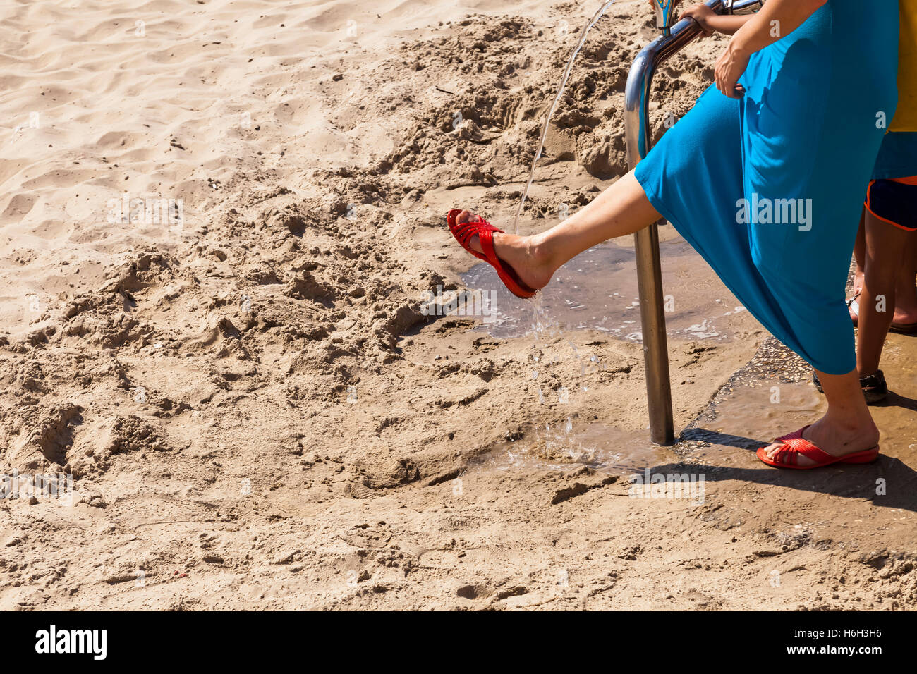 Adult woman washing the sand off her feet at the Beach Stock Photo - Alamy