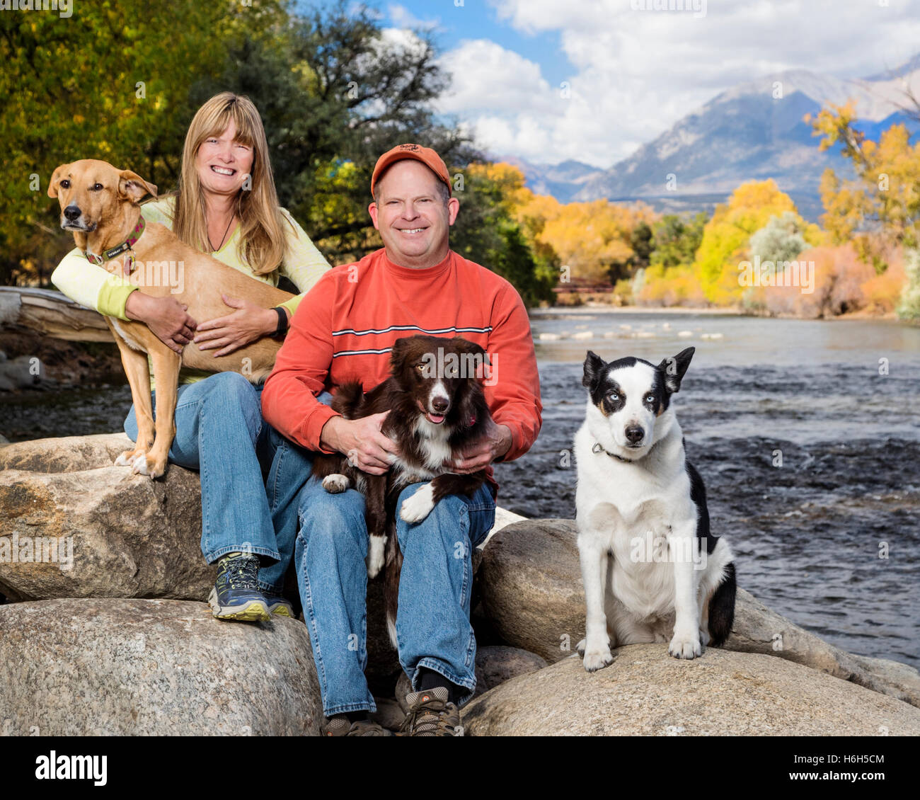 Outdoor portrait of married couple with their three dogs alongside the ...