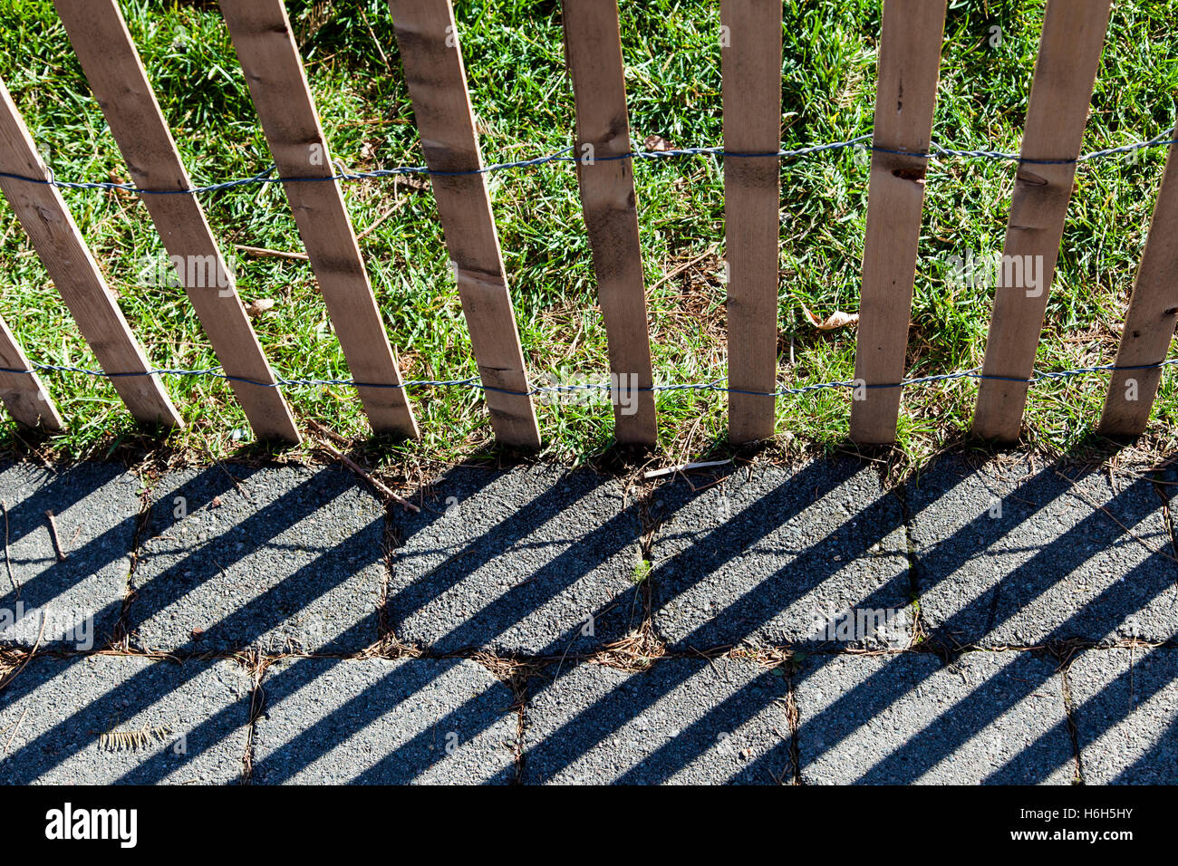 Fence made of thin wooden beams, bordering between stone tile floor and ...