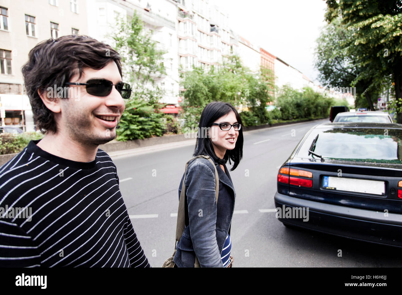 A couple in their early thirties crossing the street while having a ...