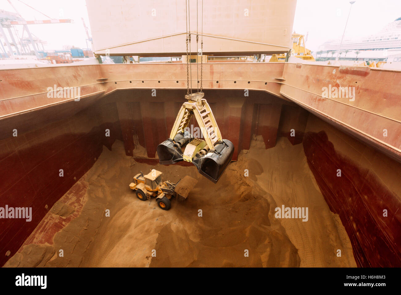 An earth mover arranging the gluten inside the pit of a grain freighter ...