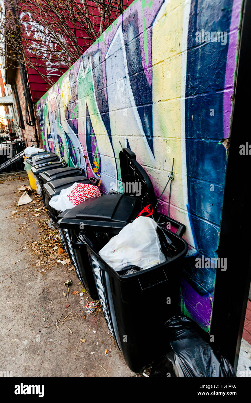 NEW-YORK - NOV 14: Full trash bins against a graffiti covered wall in ...