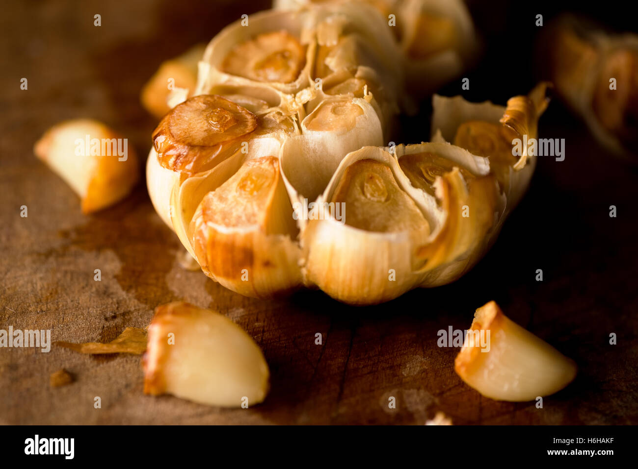 Roast whole garlic in rustic wood setting Stock Photo - Alamy