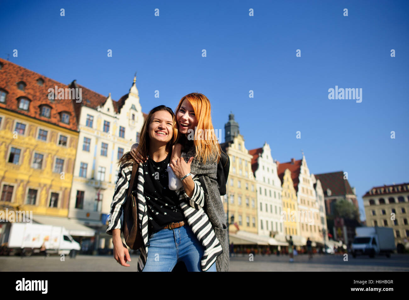 Two nice girls stand in the middle of the paved area having embraced ...