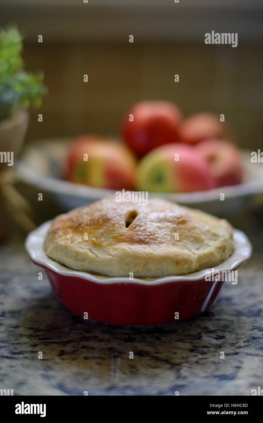 Small pie on a kitchen counter with apples in the background Stock ...