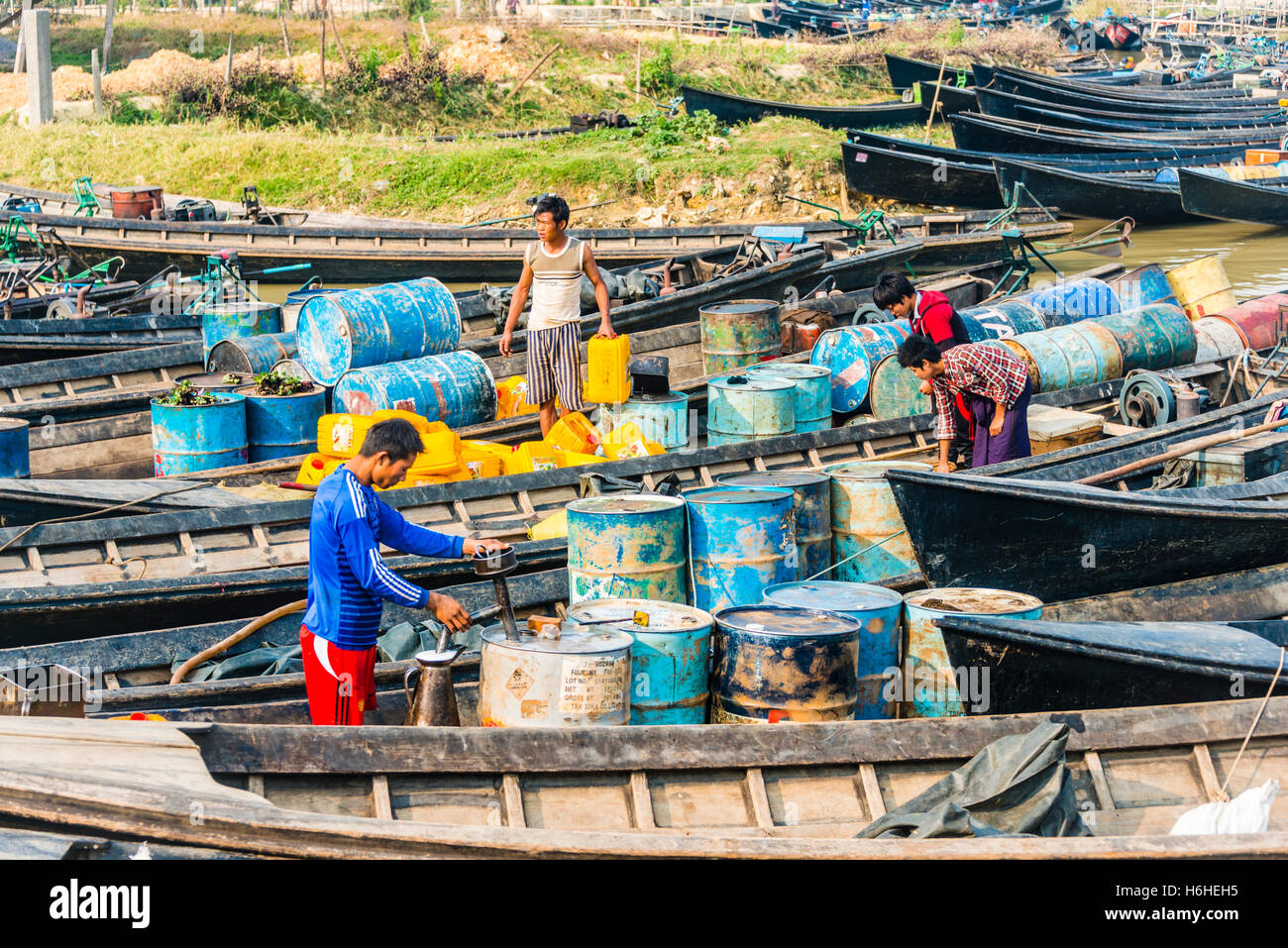 Men working in wooden boats with old oil barrels in the harbor, Nampan ...