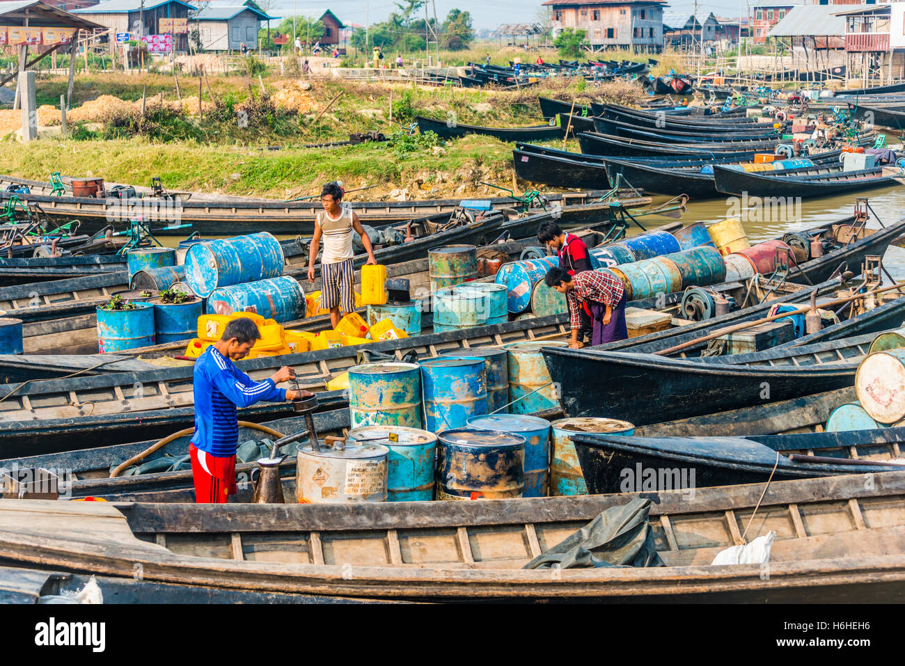 Men working in wooden boats with old oil barrels in the harbor, Nampan ...