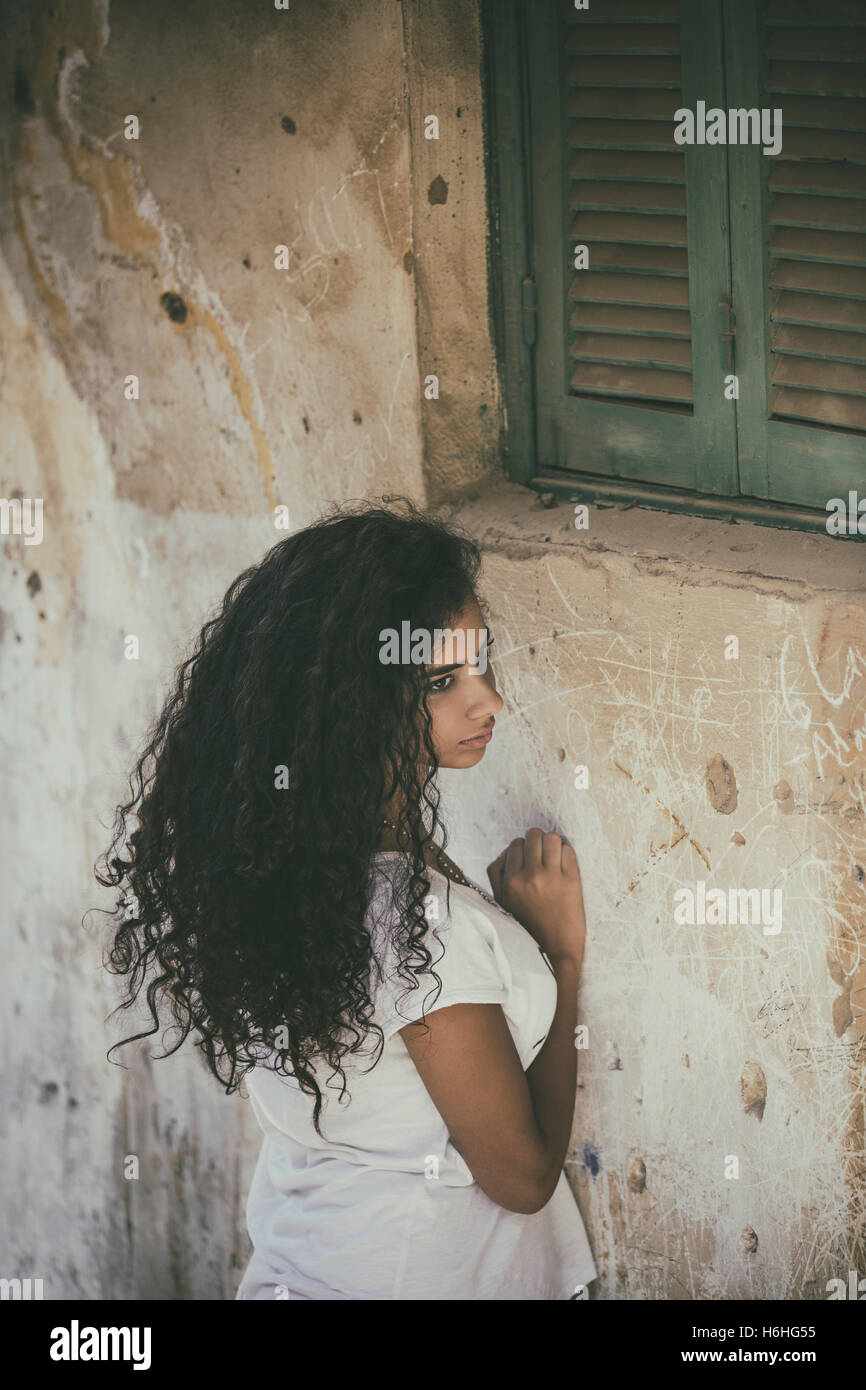 Sad young woman leaning against the wall outdoors Stock Photo - Alamy