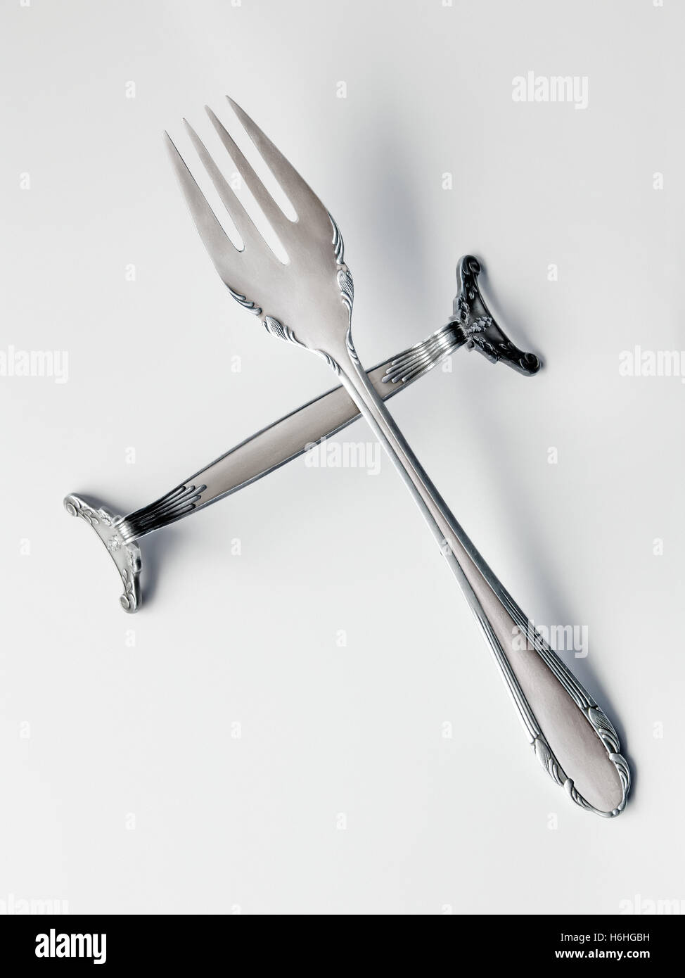 Close-up of Victorian silver fork on silver knife rest. On white ...