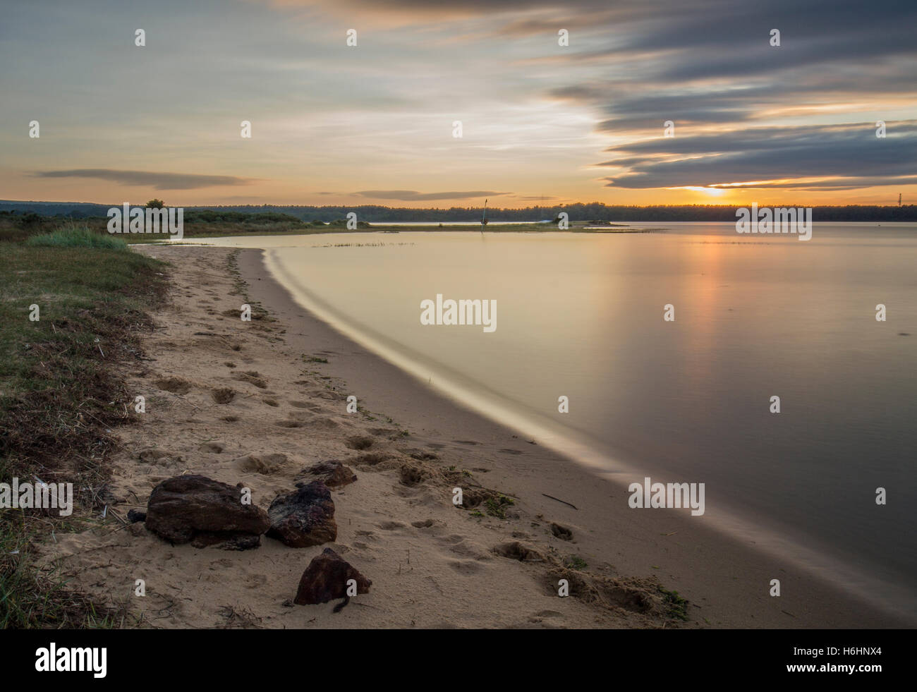 long exposure of evening sun on sandy and rocky beach Stock Photo - Alamy