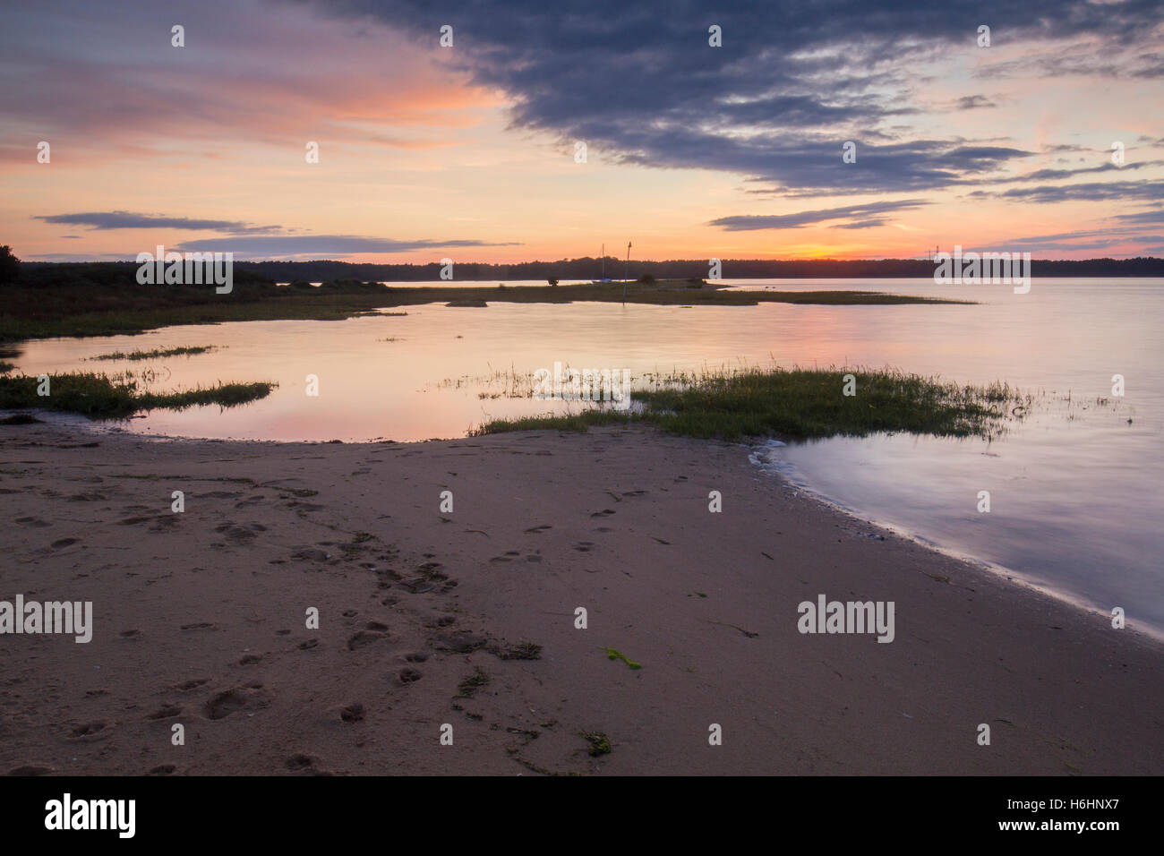 sunset over bay with footprints in sand Stock Photo - Alamy