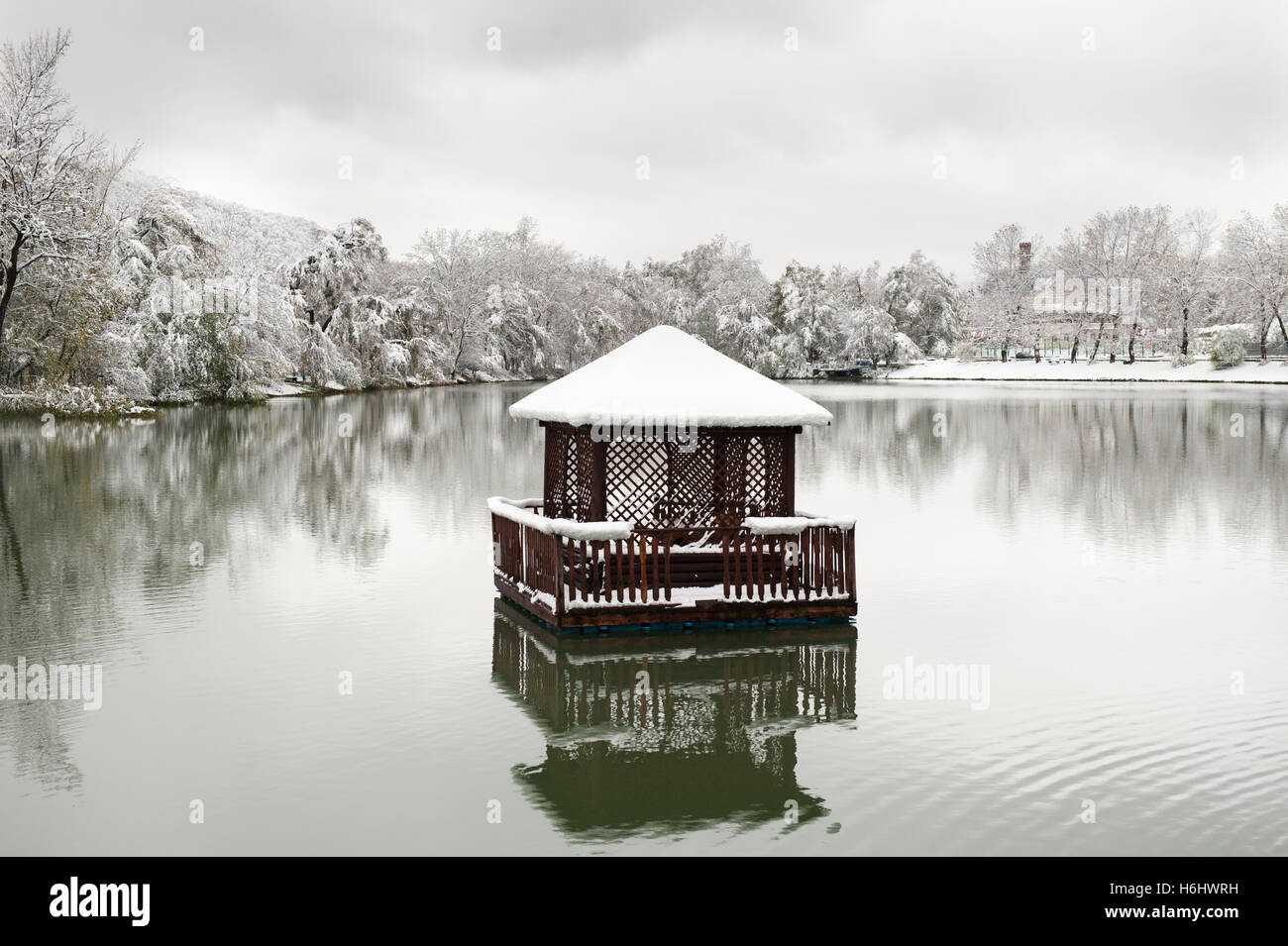 floating gazebo covered with snow in the middle of the lake in the park ...