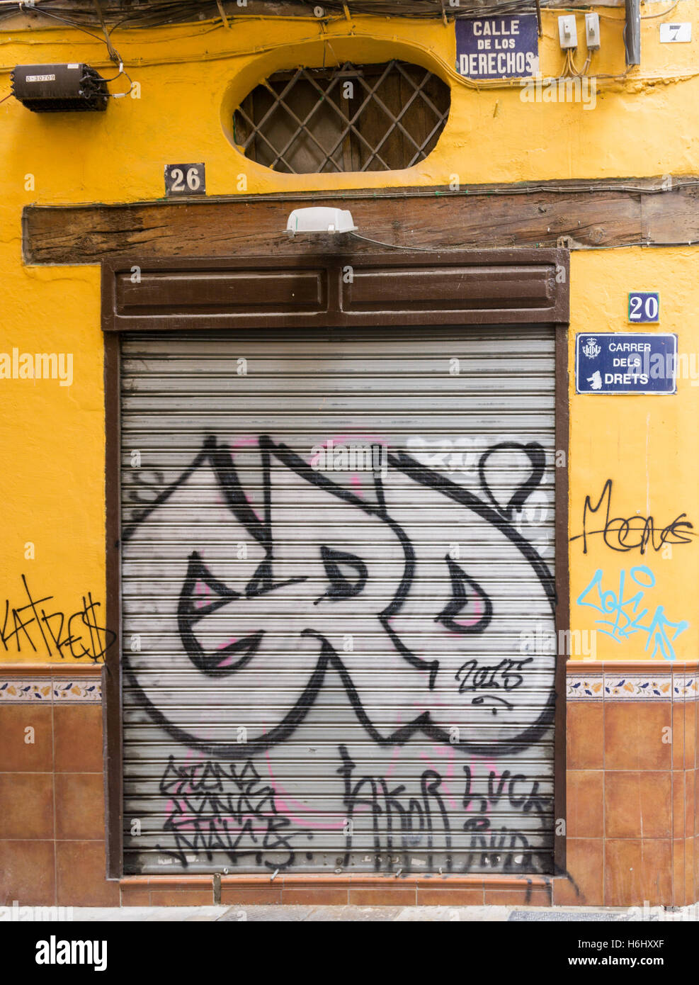 Spray painted graffiti on a closed shutter and street signs in Catalan ...