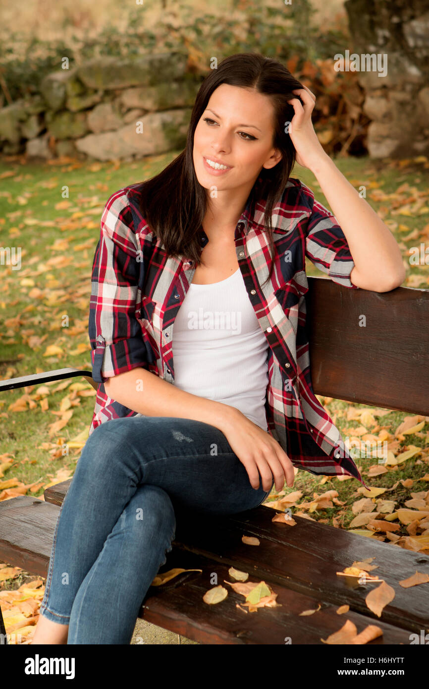 Beautiful young woman sitting on a bench in park at fall Stock Photo ...