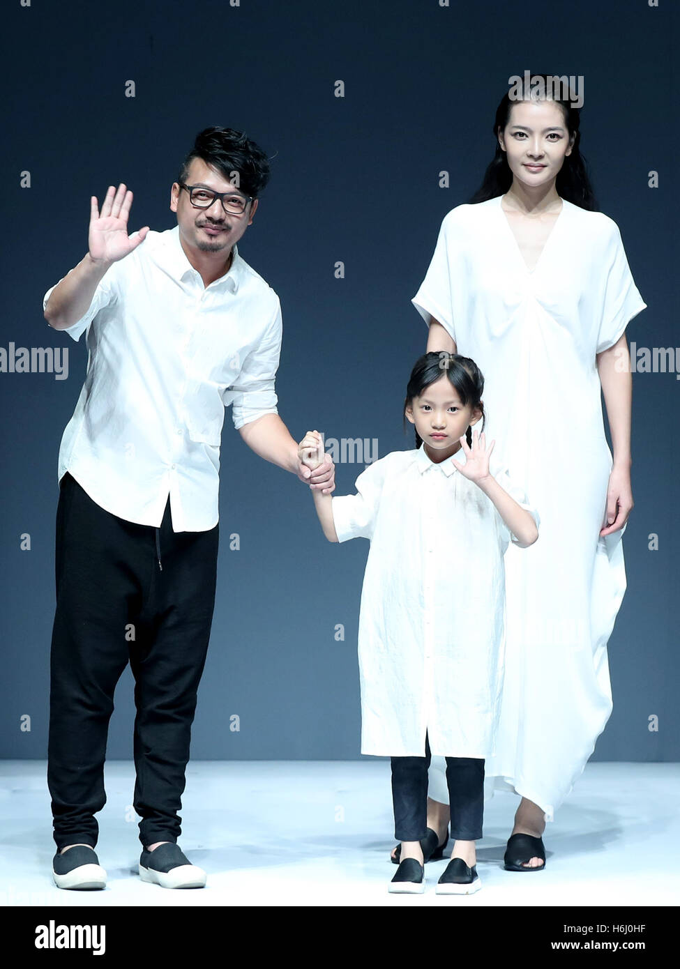 Beijing, China. 28th Oct, 2016. Designer Li Zhen (L) and models greet ...