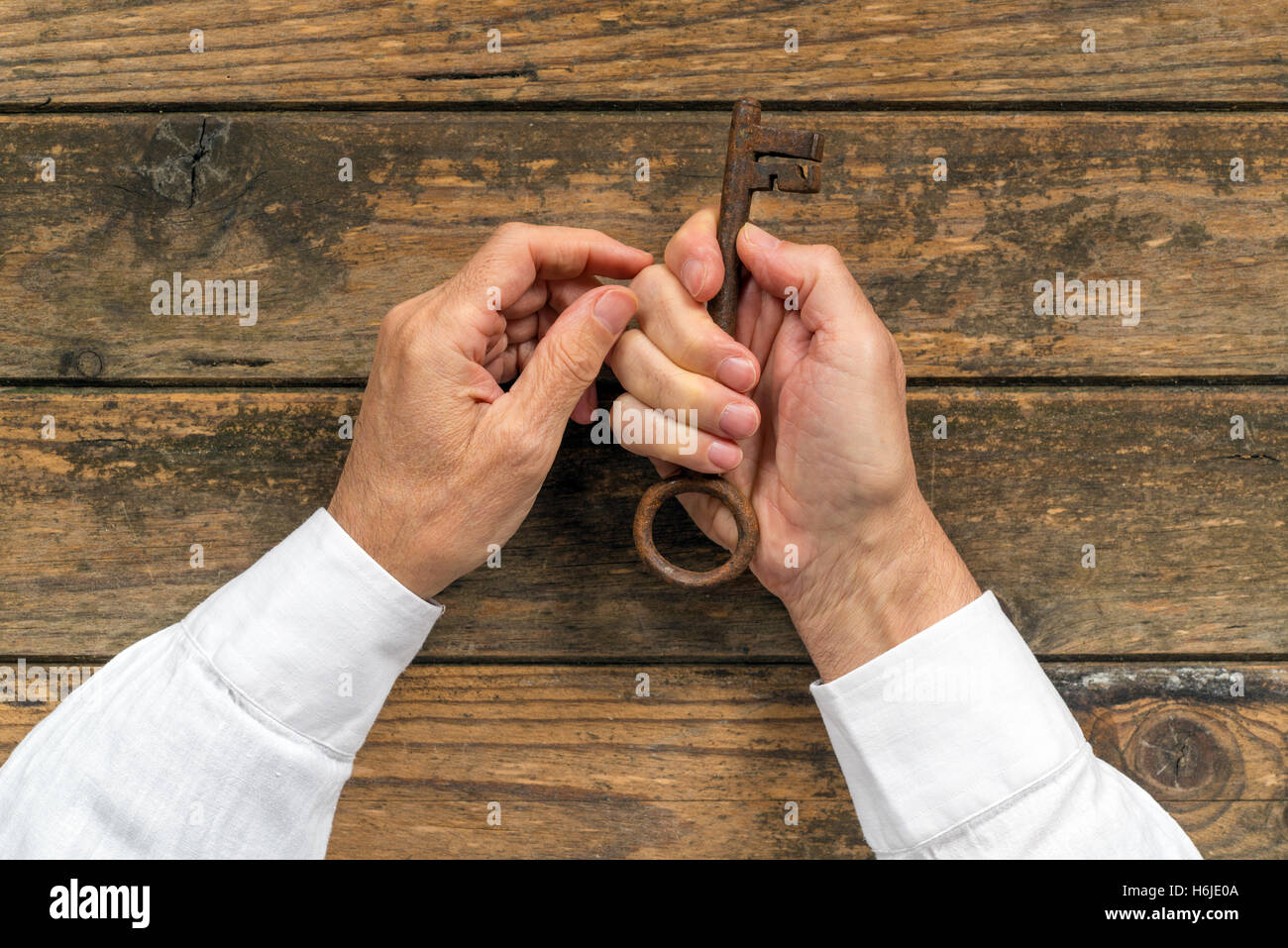 Man holding a big old antique skeleton key in his hands. Wooden ...