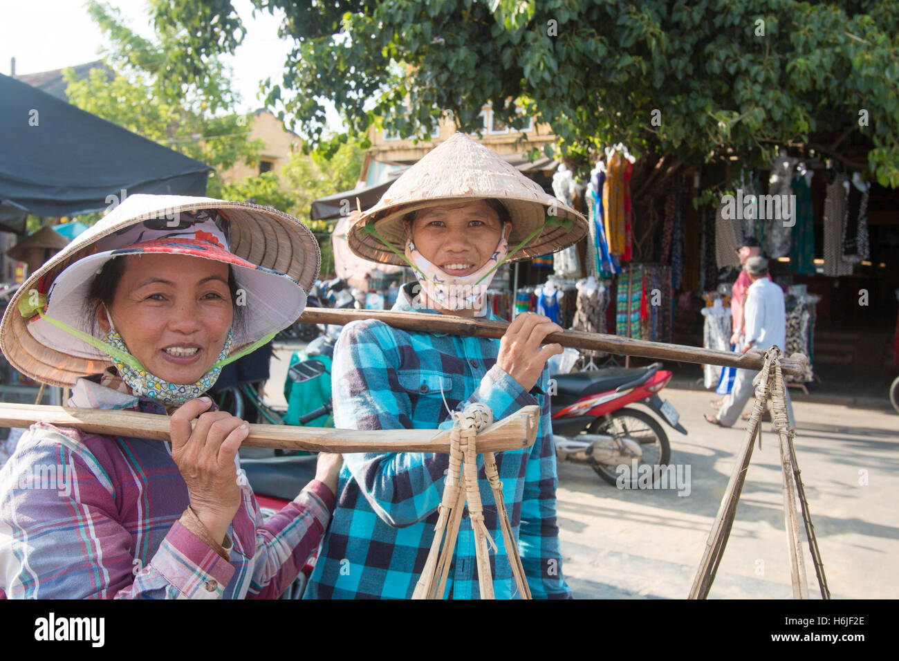 Two vietnamese ladies in Hoi An each carrying a bamboo yoke carrying ...